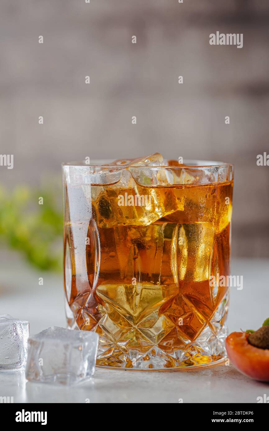 Glass of peach or apricot iced tea with fruit slices against white ...
