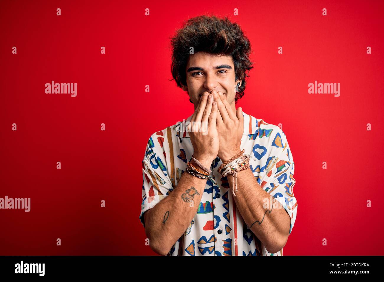 Young handsome man on vacation wearing summer shirt over isolated red ...