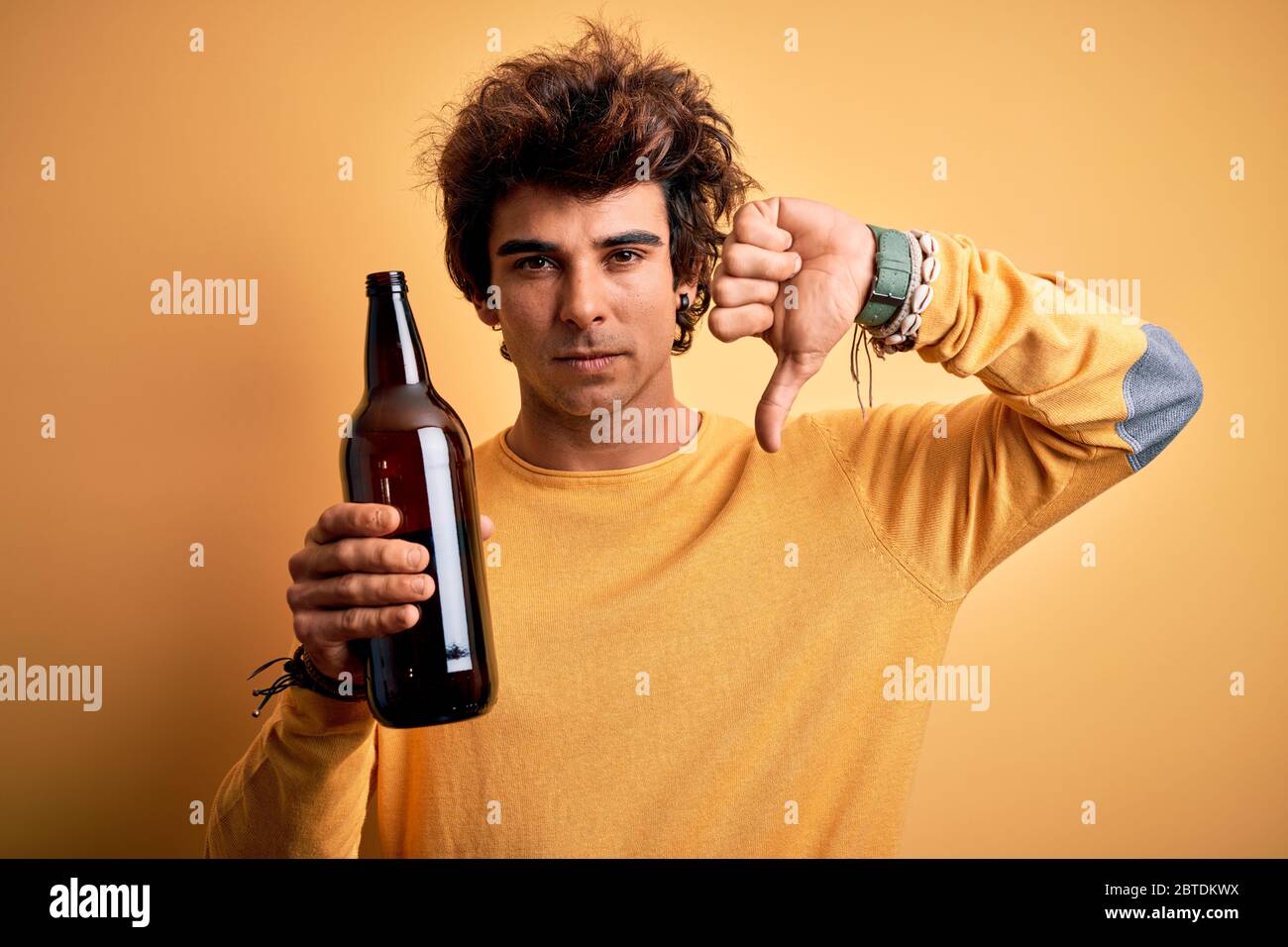Young handsome man drinking bottle of beer standing over isolated ...