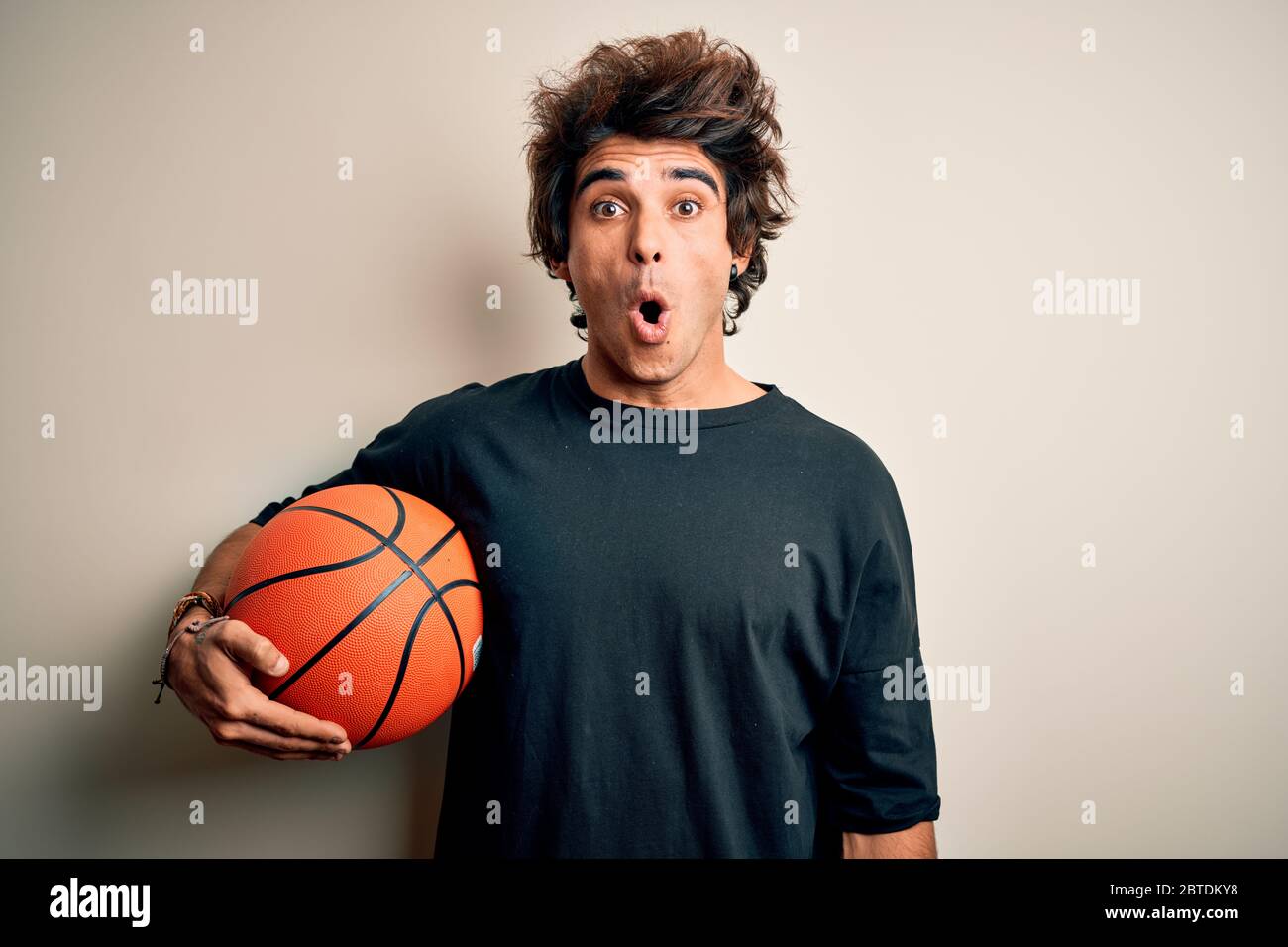 Young handsome sportsman holding basketball ball standing over isolated ...