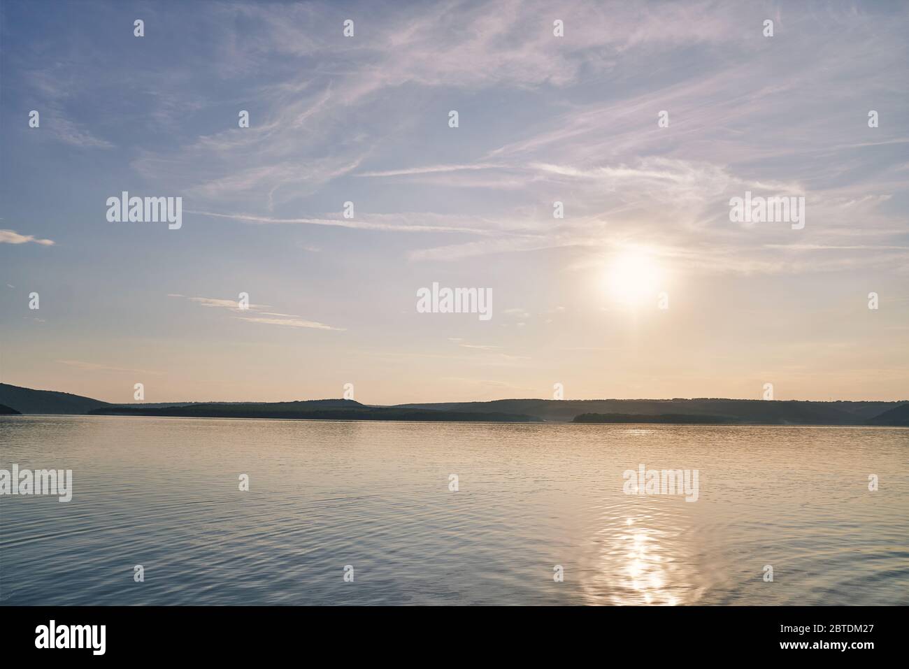 Summer evening on lake. Sun track on water at sunset. Rocky shore of ...