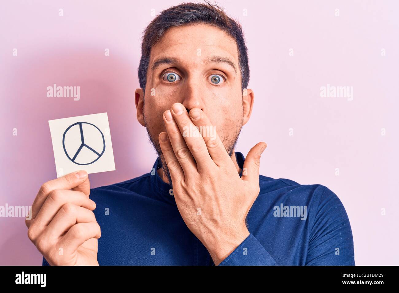 Young handsome man holding reminder with peace symbol over isolated ...
