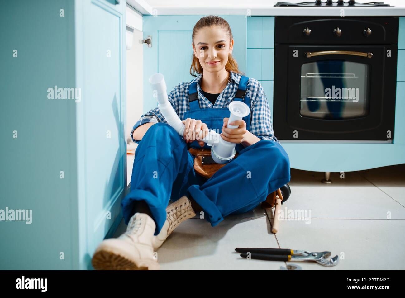 Cute female plumber in uniform holds drain pipe Stock Photo - Alamy