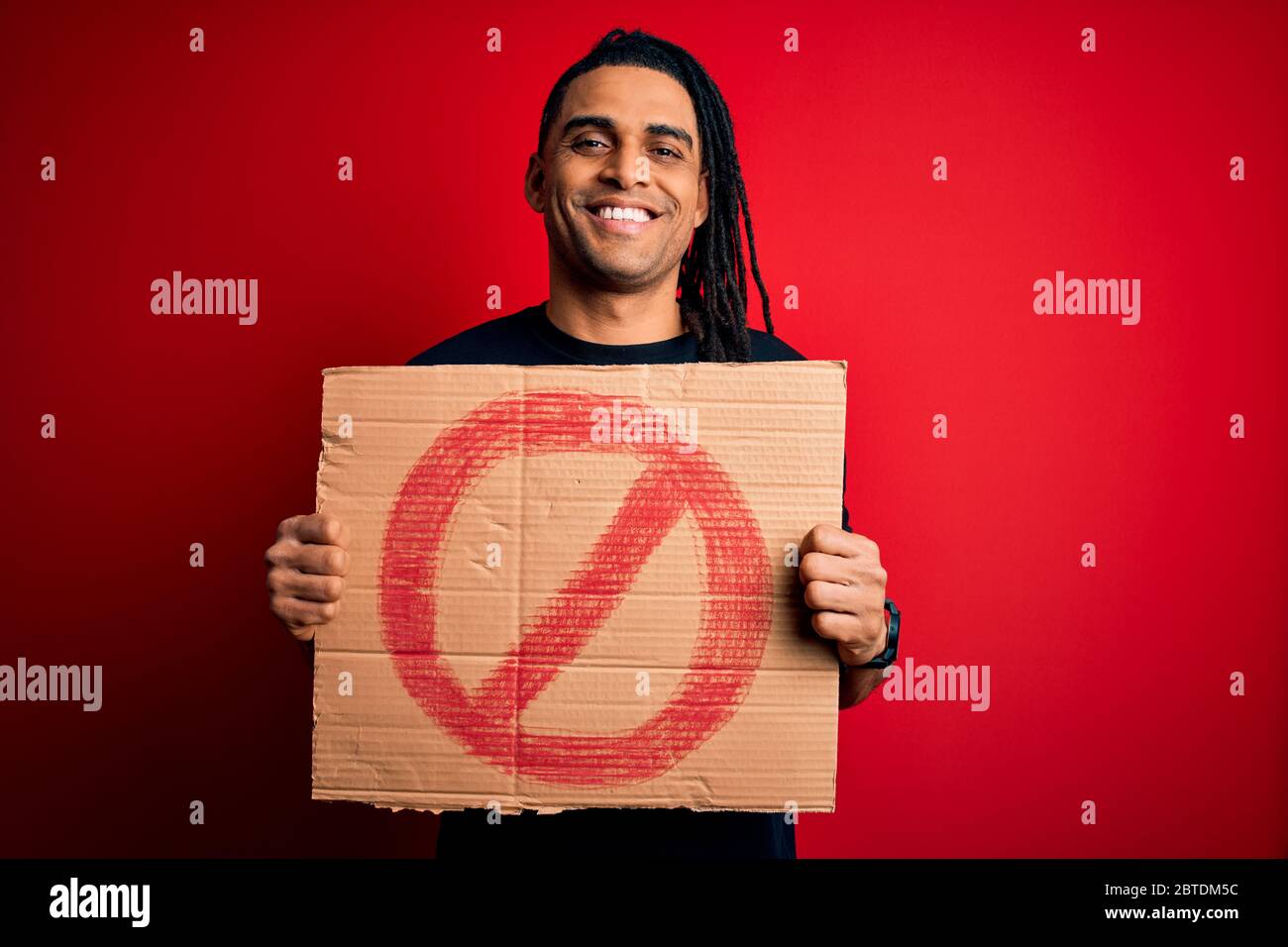 Young handsome african american man with dreadlocks holding banner with ...