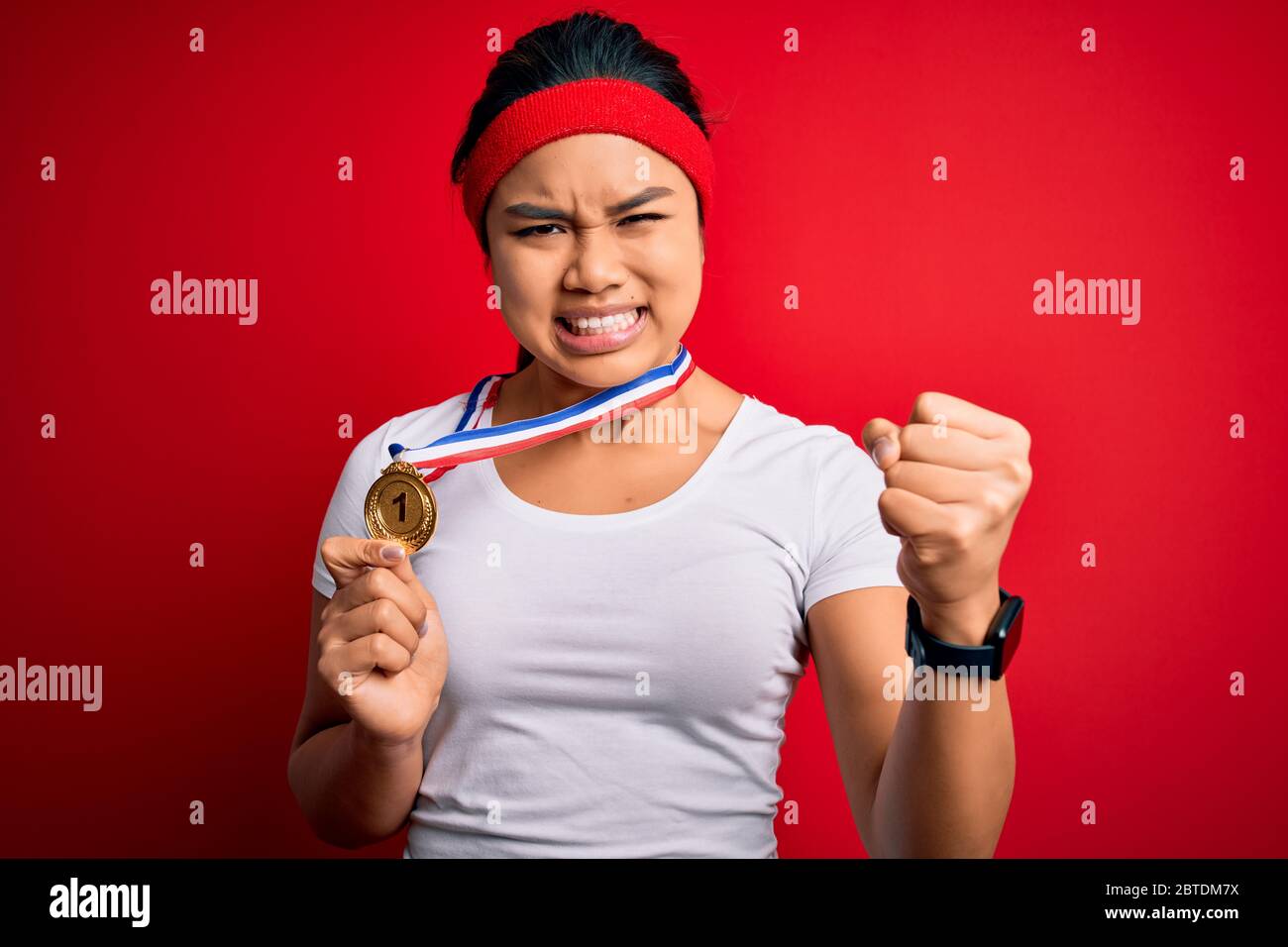 Young asian champion girl winning medal standing over isolated red ...