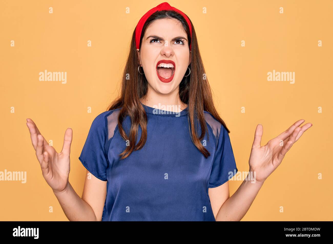 Young beautiful brunette woman wearing red lips over yellow background ...