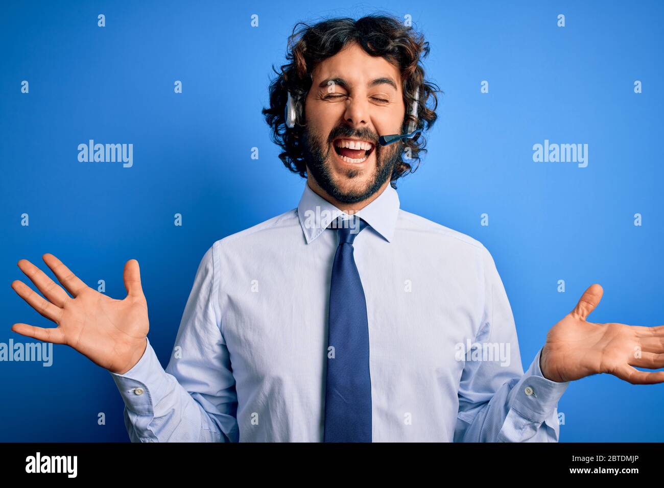 Young handsome call center agent man with beard working using headset ...