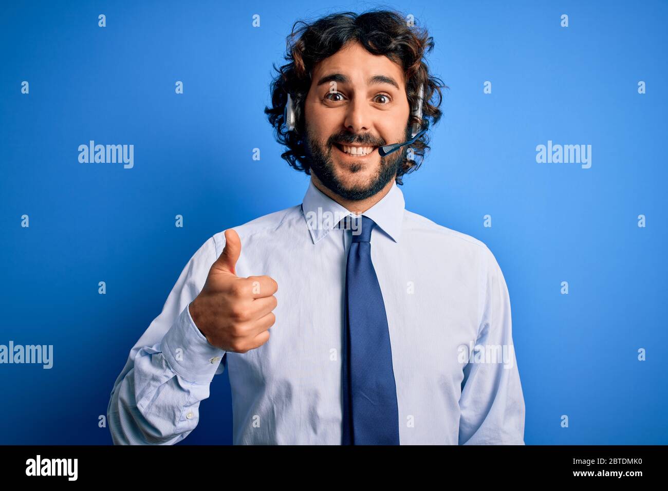 Young handsome call center agent man with beard working using headset ...
