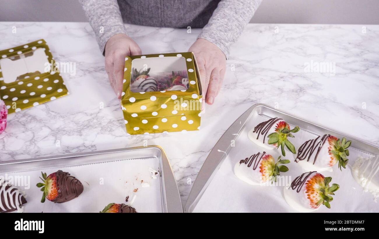 Step by step. Packaging chocolate dipped strawberries into a paper box ...