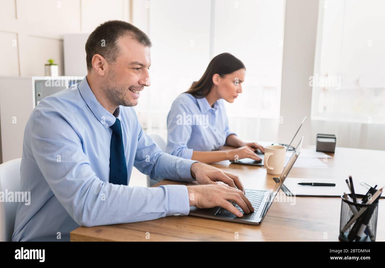 Two Office Managers Working On Laptop Computers At Workplace Indoors ...