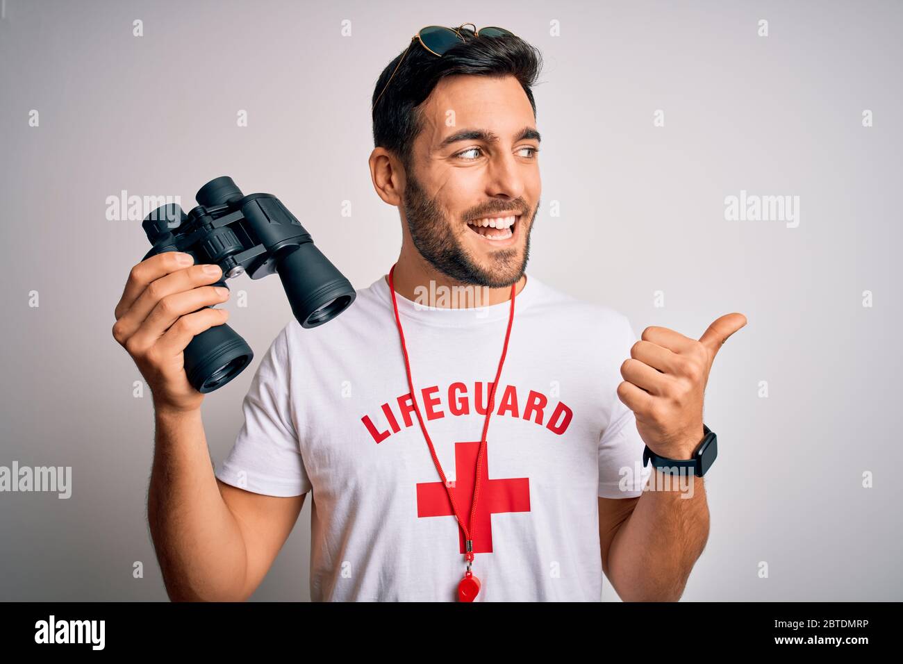 Young lifeguard man with beard wearing t-shirt with red cross and ...