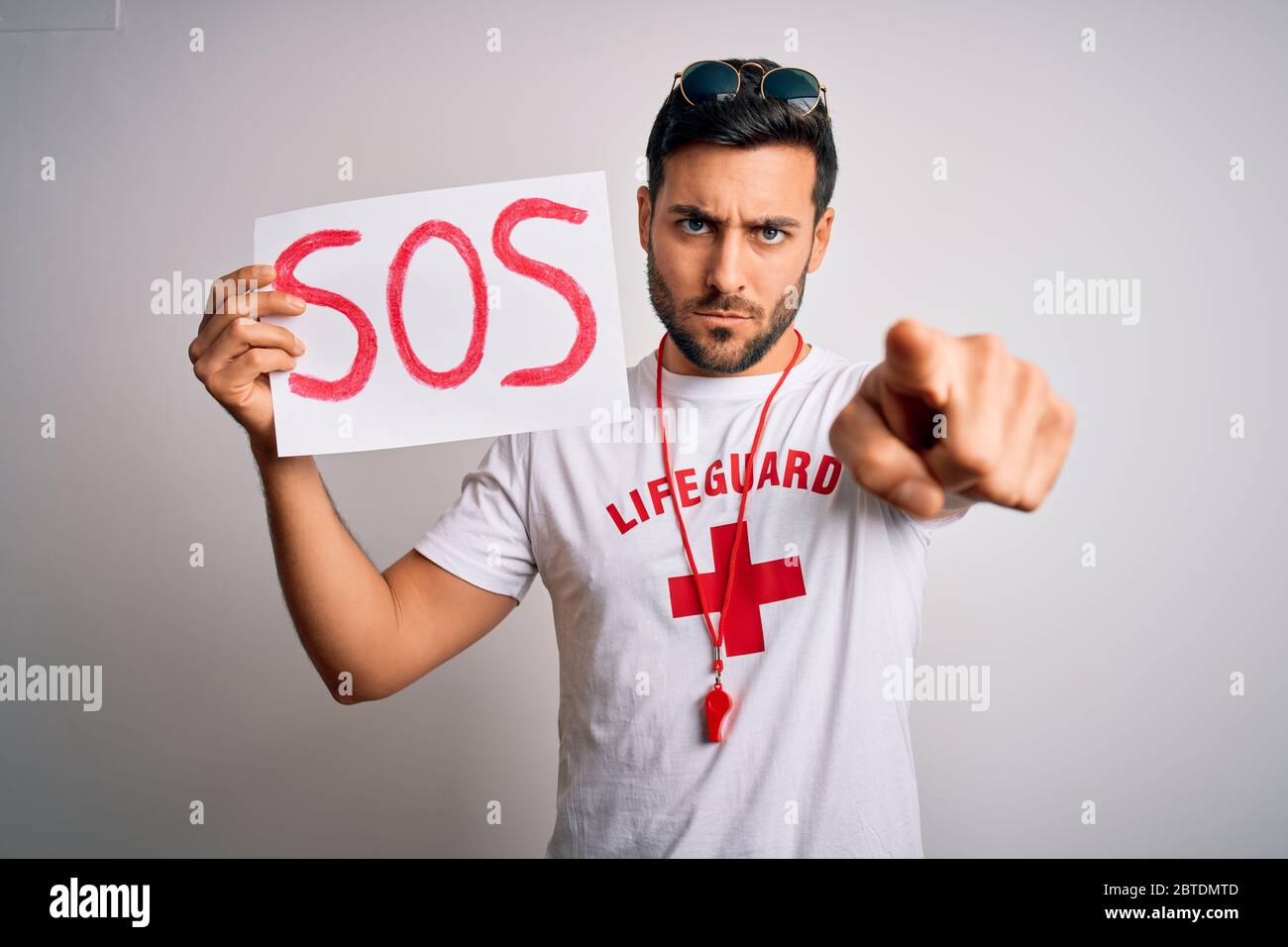 Young lifeguard man with beard wearing whistle holding paper with sos ...