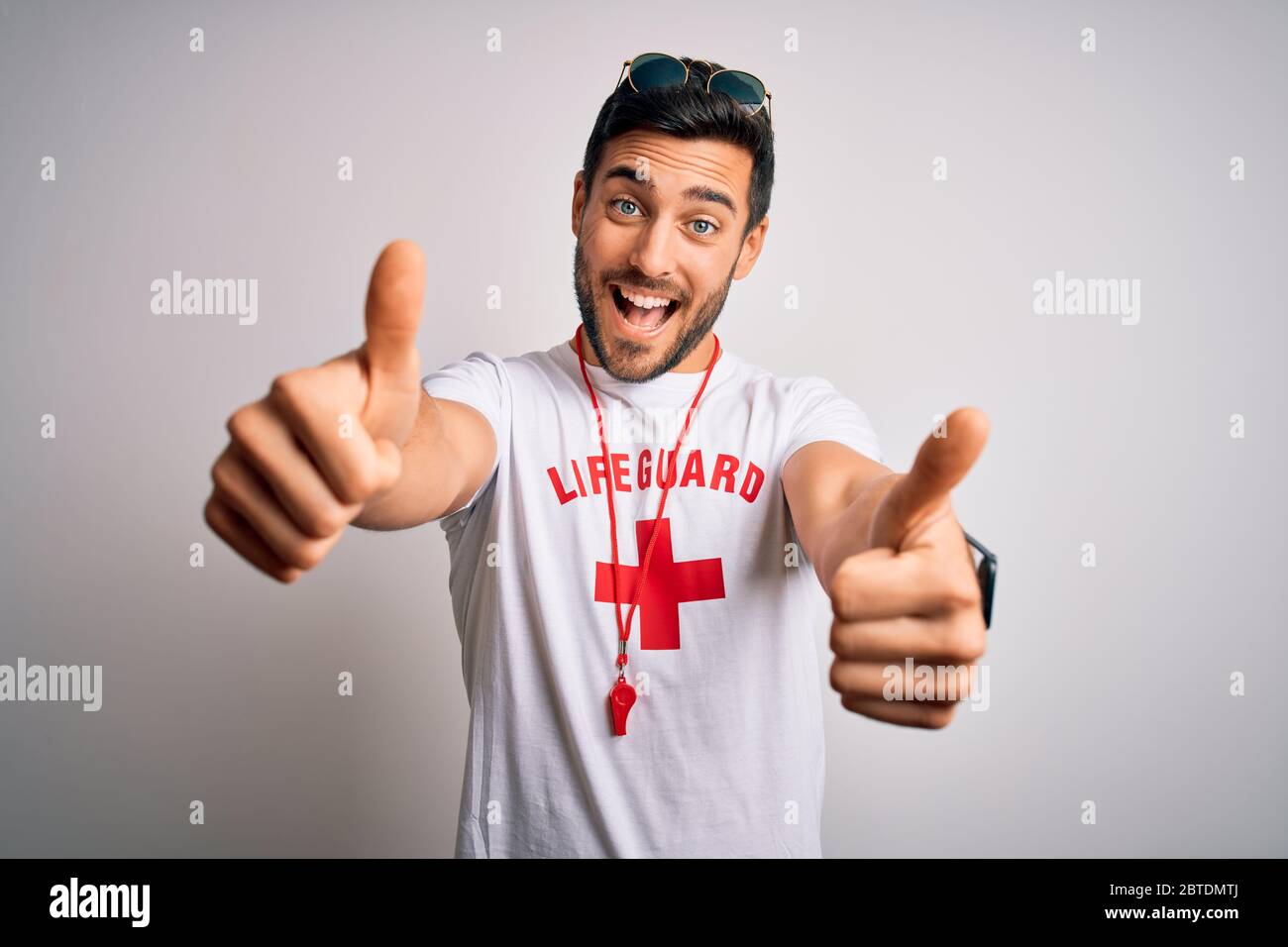 Young handsome lifeguard man with beard wearing t-shirt with red cross ...