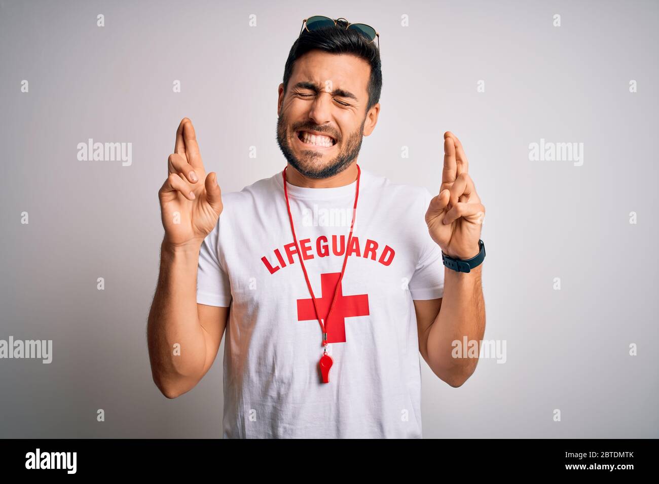 Young handsome lifeguard man with beard wearing t-shirt with red cross ...