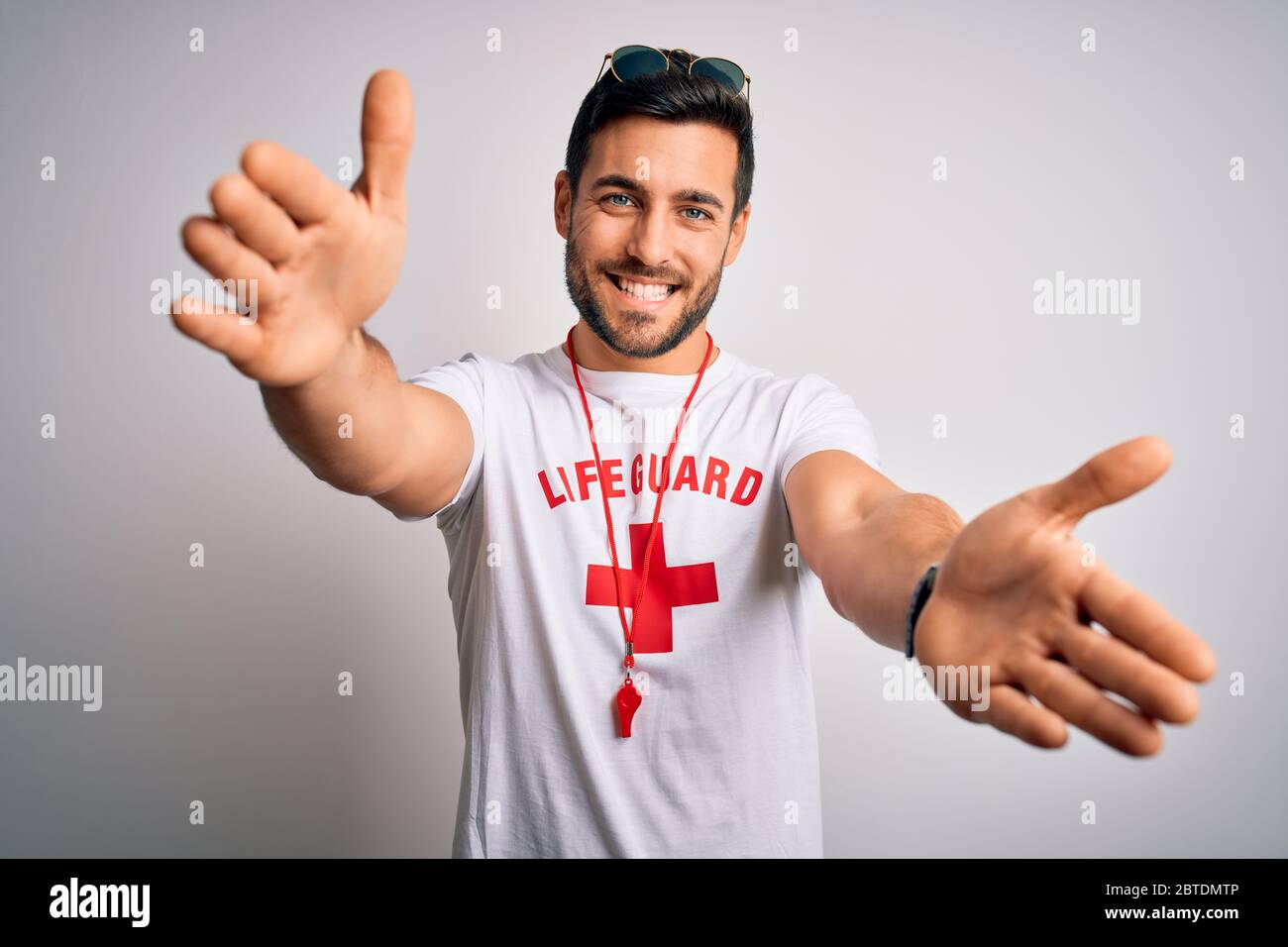 Young handsome lifeguard man with beard wearing t-shirt with red cross ...