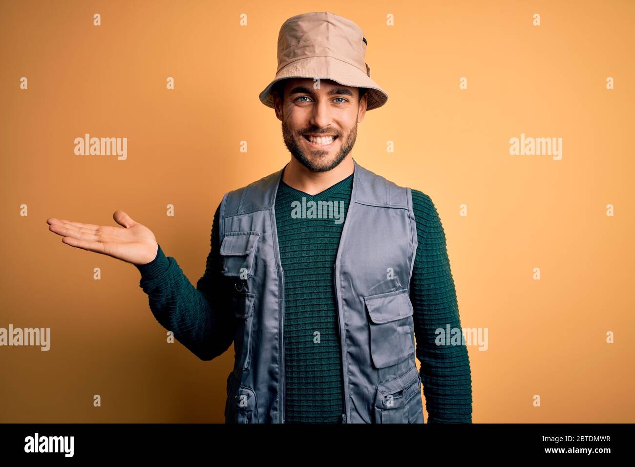 Handsome tourist man with beard on vacation wearing explorer hat over ...