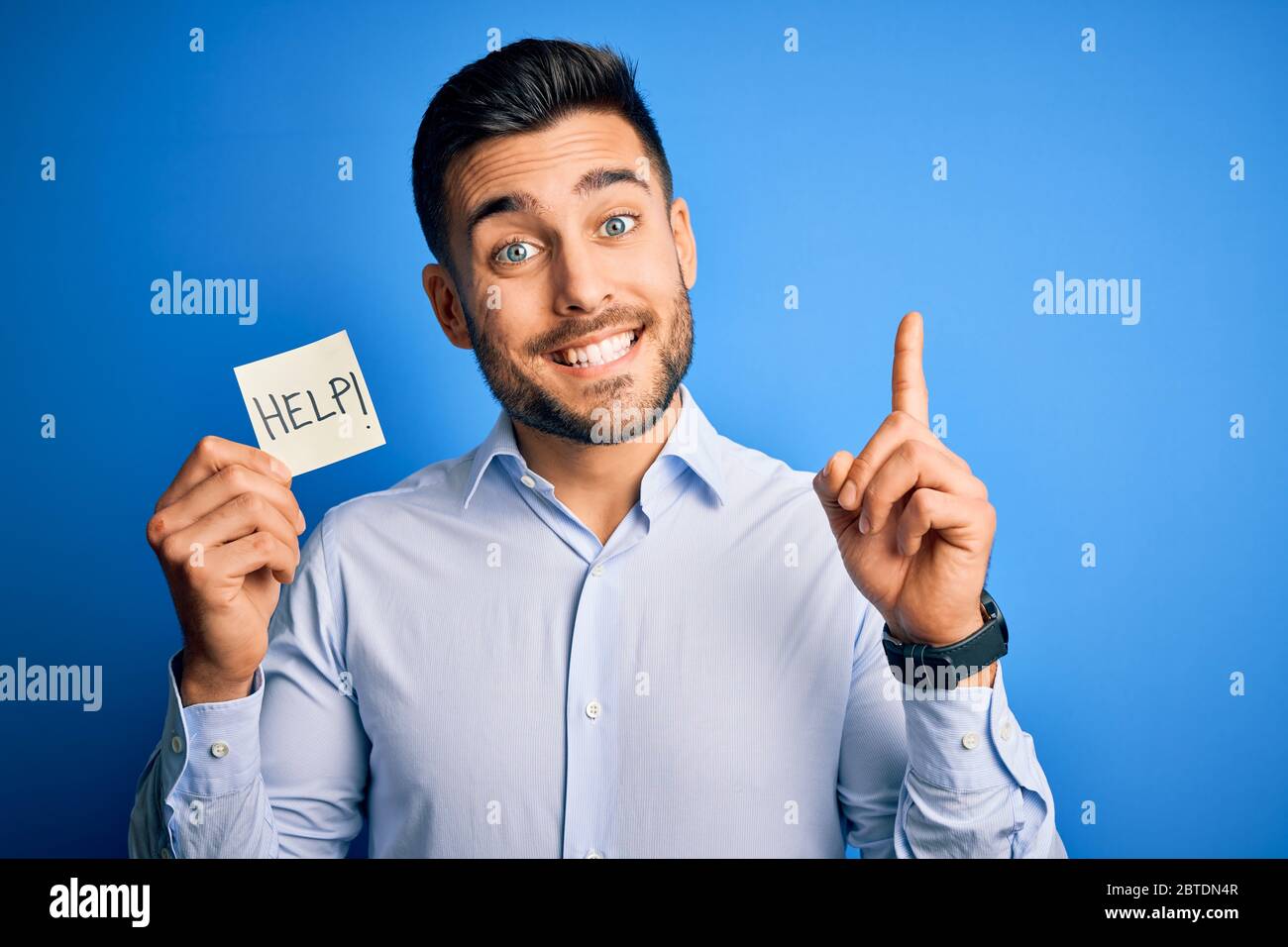 Young overworked business man asking for help holding paper over blue ...