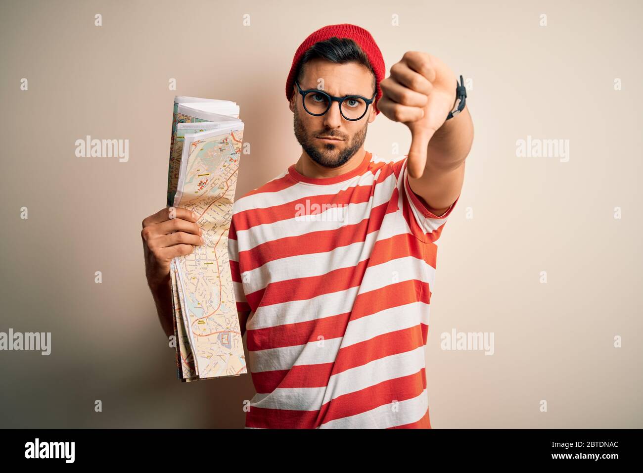 Young handsome tourist man on vacation wearing glasses holding city map ...