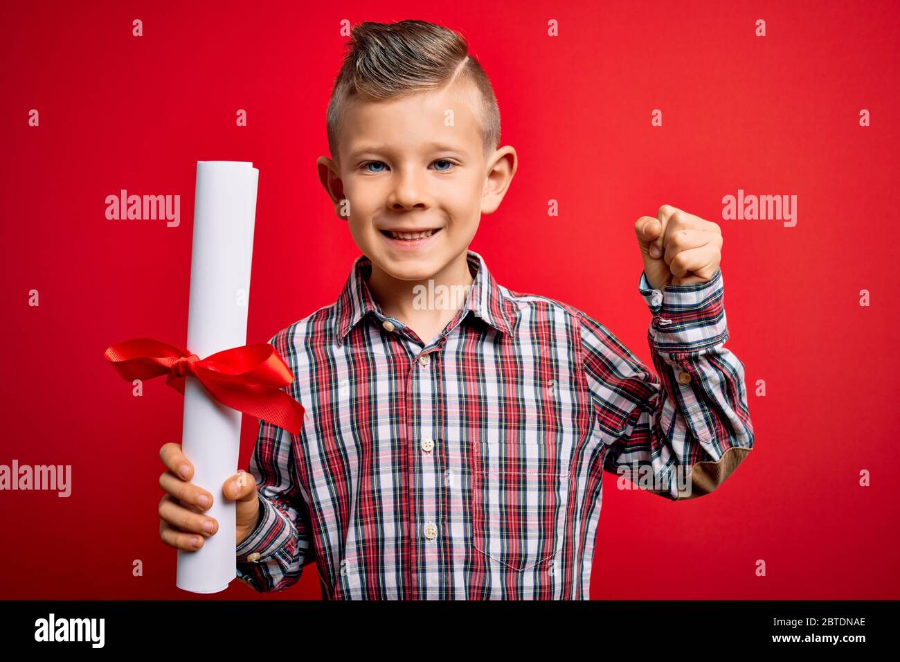 Young little caucasian student kid holding school degree over red ...