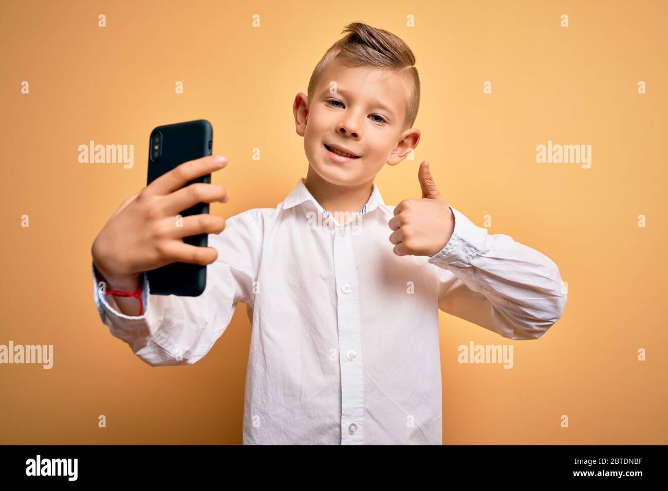 Young little caucasian kid using smartphone and looking at the screen ...