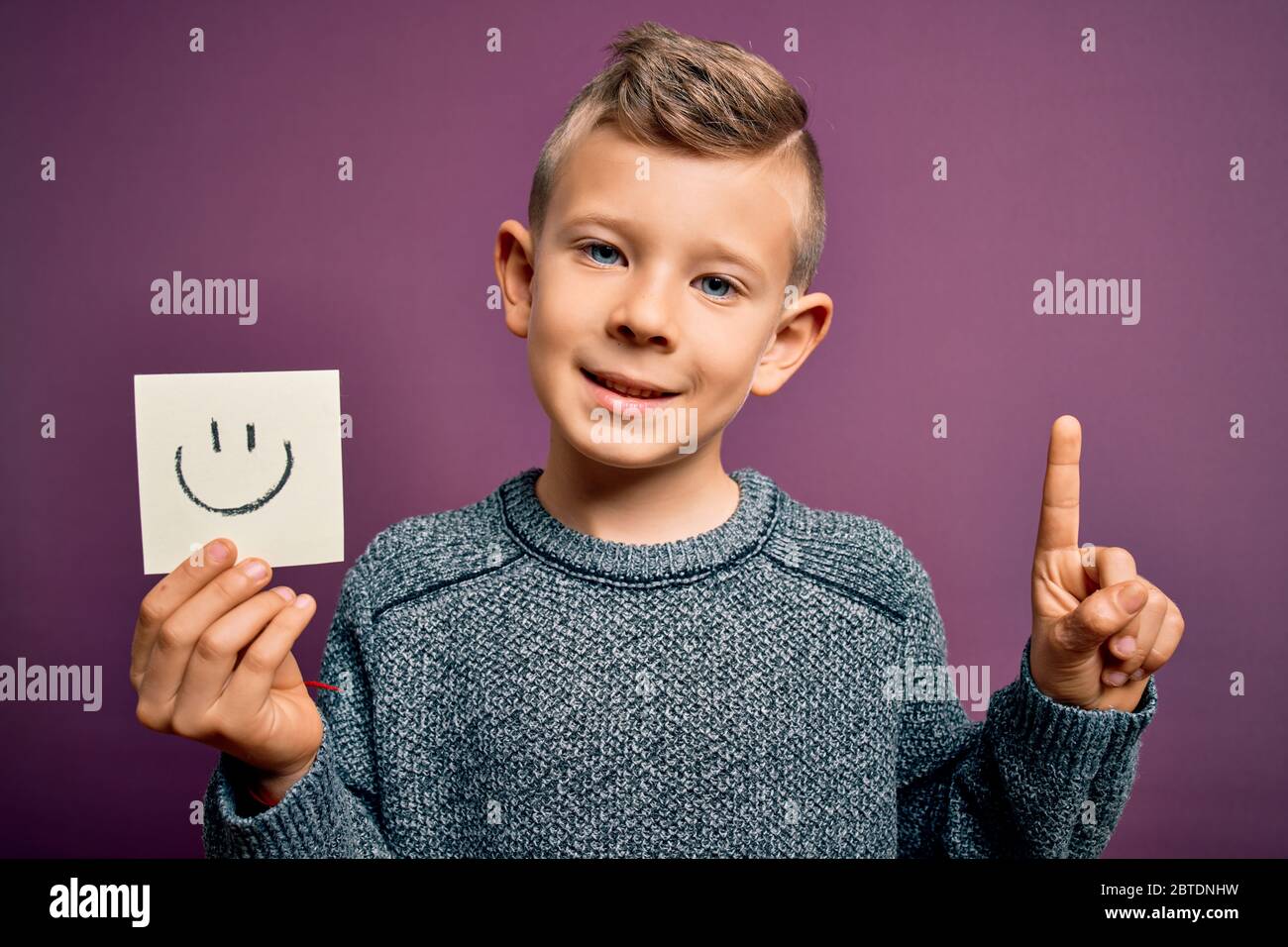 Young little caucasian kid showing smiley face on a paper note as happy ...