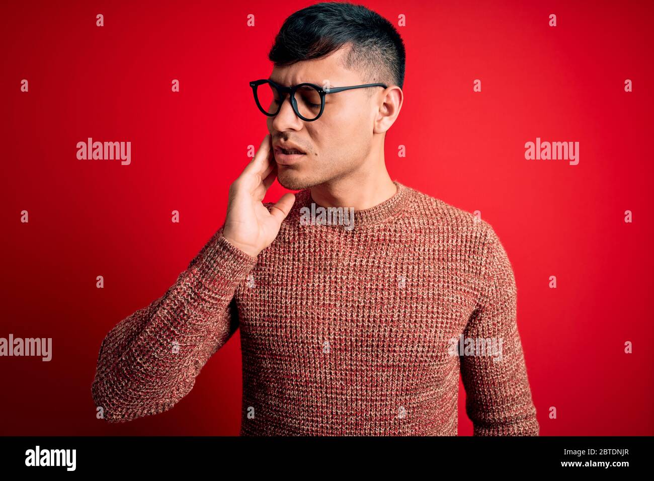 Young handsome hispanic man wearing nerd glasses over red background ...