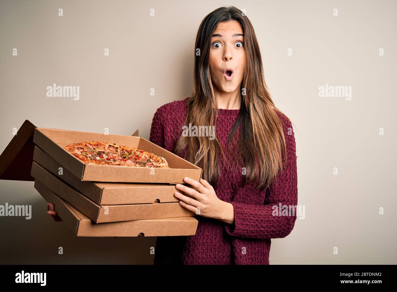 Young beautiful girl holding delivery boxes with Italian pizza standing ...