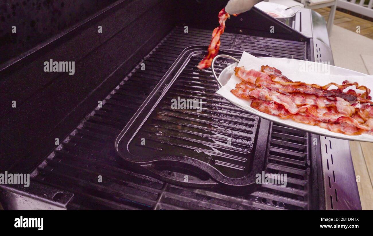 Cooking bacon stips on an outdoor gas grill Stock Photo - Alamy