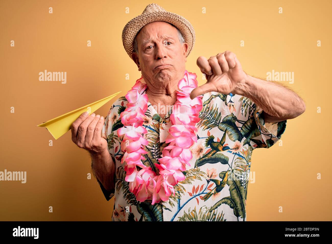 Grey haired senior man wearing summer hat and hawaiian lei holding ...
