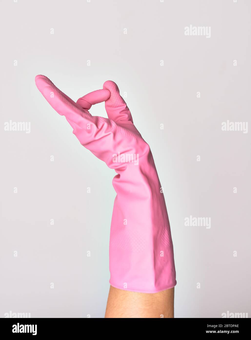 Hand of caucasian young woman wearing pink cleaning glove doing ok sign ...