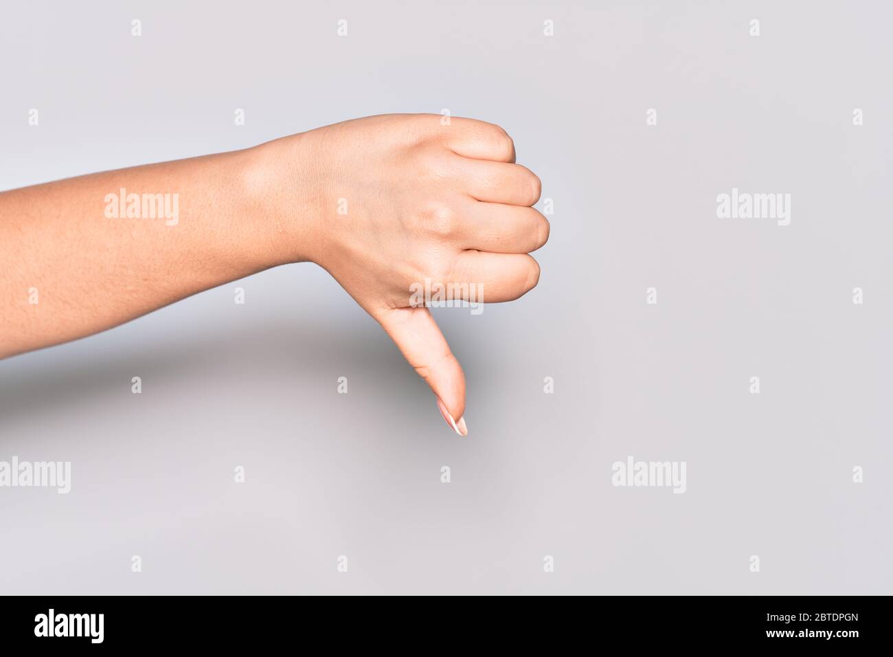Hand of caucasian young woman doing thumbs down rejection gesture ...