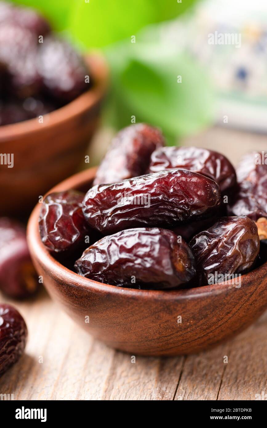 Dried medjool dates in bowl on wooden table background. Arabic Eastern ...
