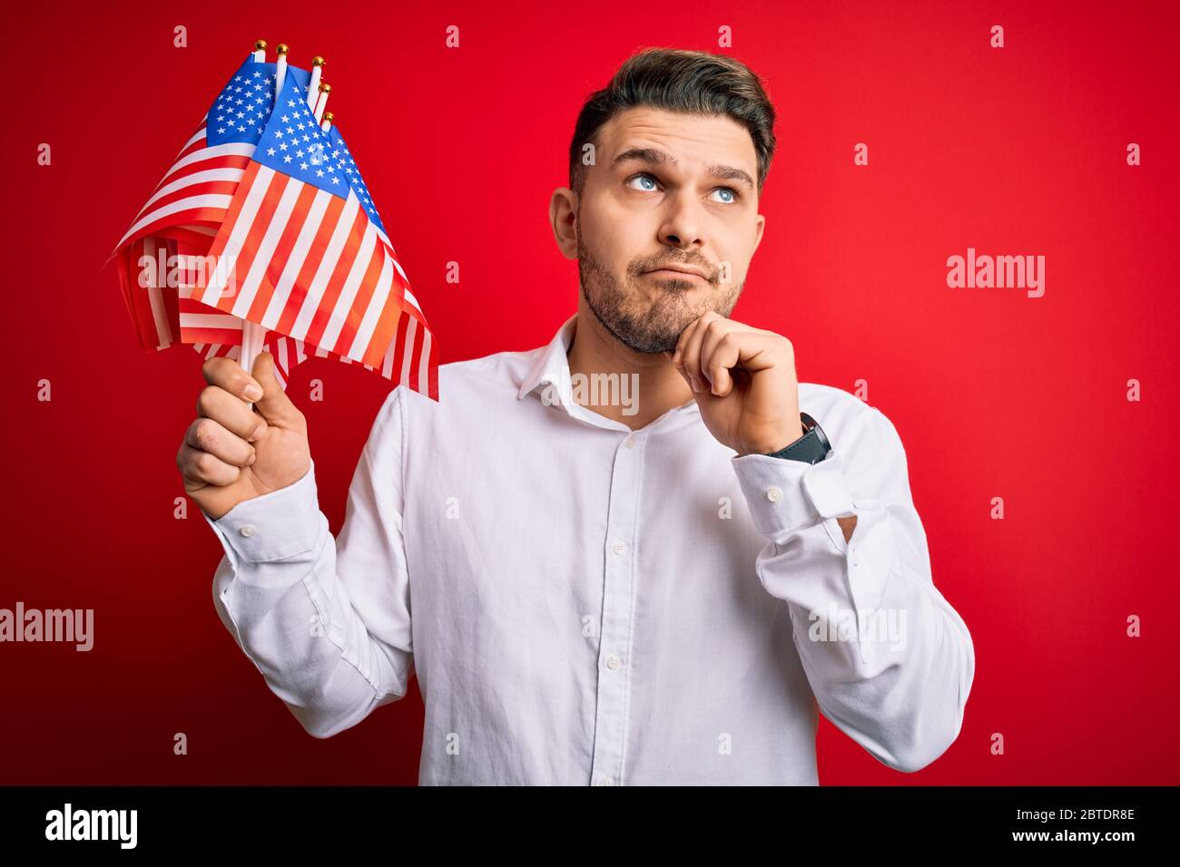 Young man with blue eyes holding flag of united states of america over ...