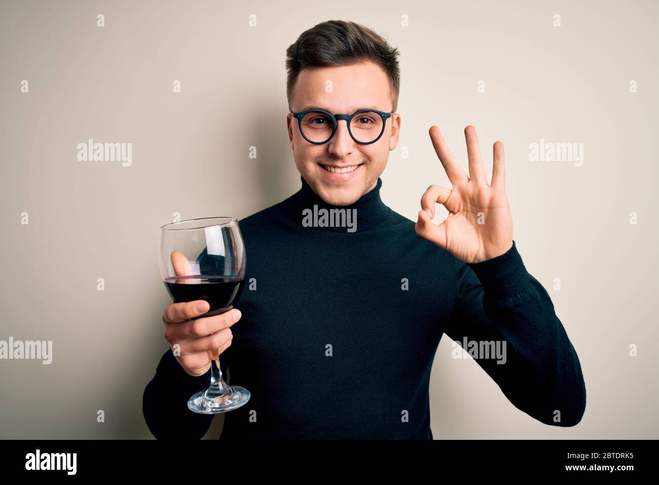 Young handsome caucasian man drinking an alcoholic glass of red wine ...