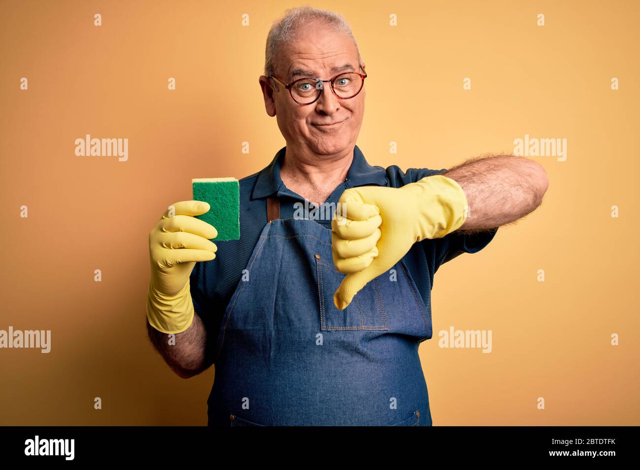 Middle age hoary cleaner man cleaning wearing apron and gloves using ...