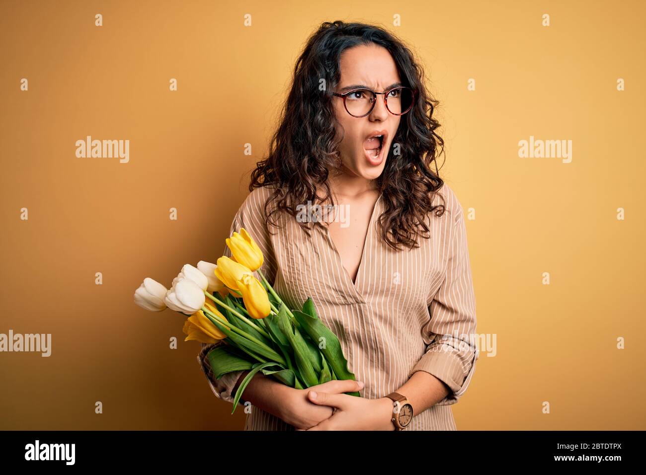 Young beautiful romantic woman with curly hair holding bouquet of ...