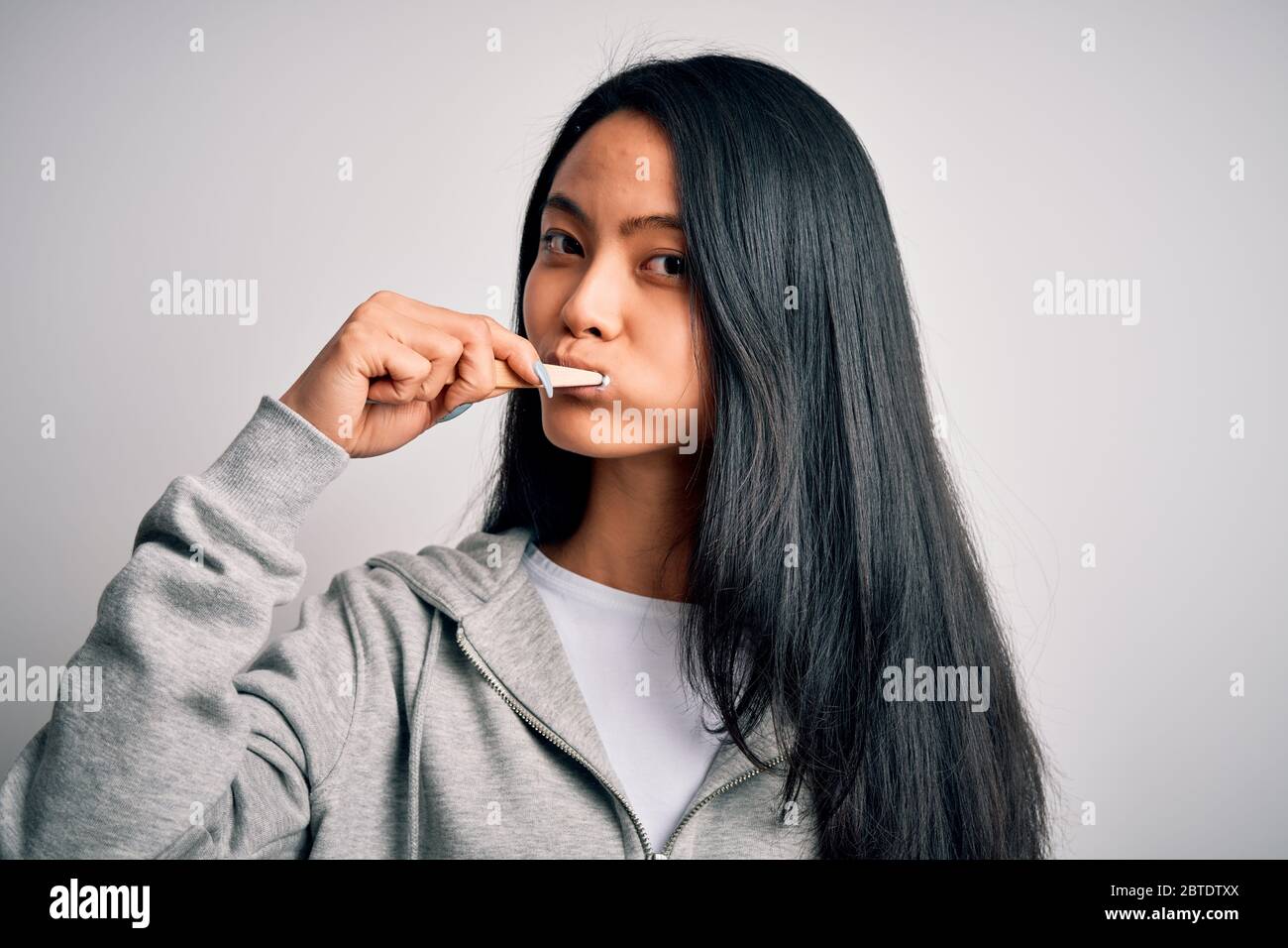 Young beautiful woman standing whasing tooth using toothbrush over ...