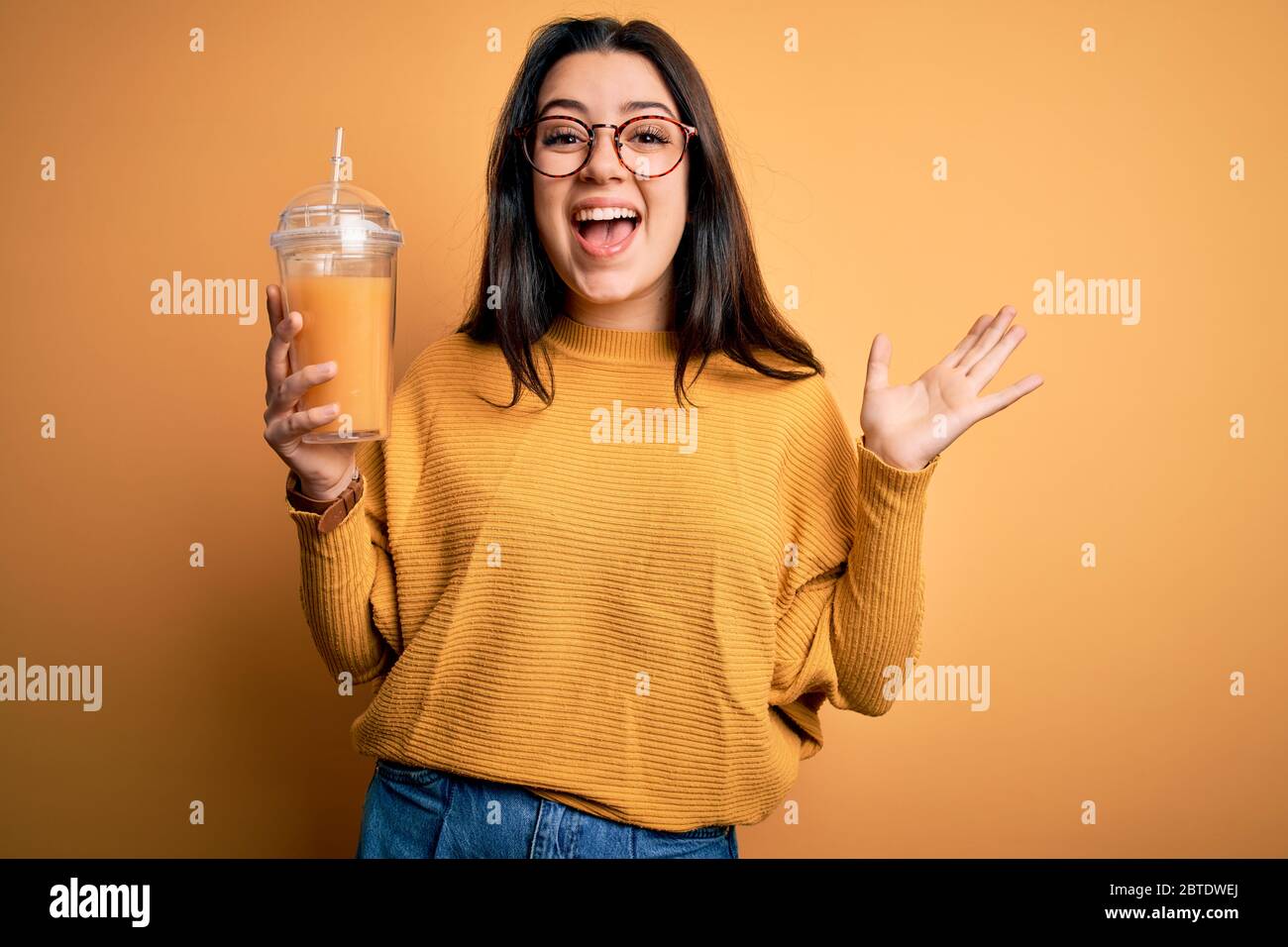 Young brunette woman drinking fresh orange juice from take away bottle ...