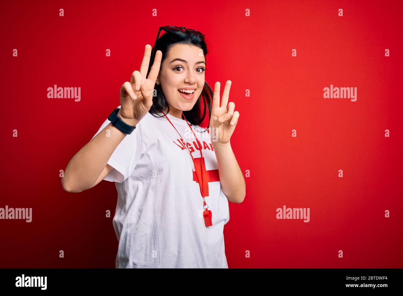 Young lifeguard woman wearing secury guard equipent over red background ...