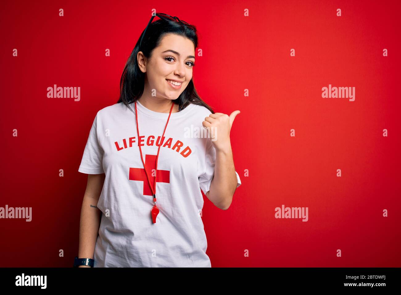 Young lifeguard woman wearing secury guard equipent over red background ...