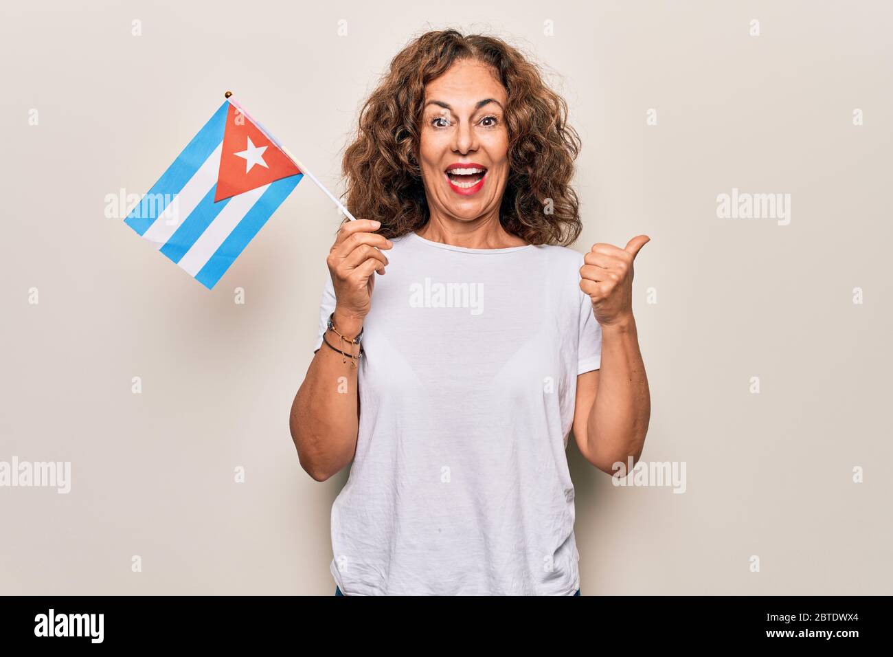 Middle age beautiful tourist woman holding cuban flag over isolated ...