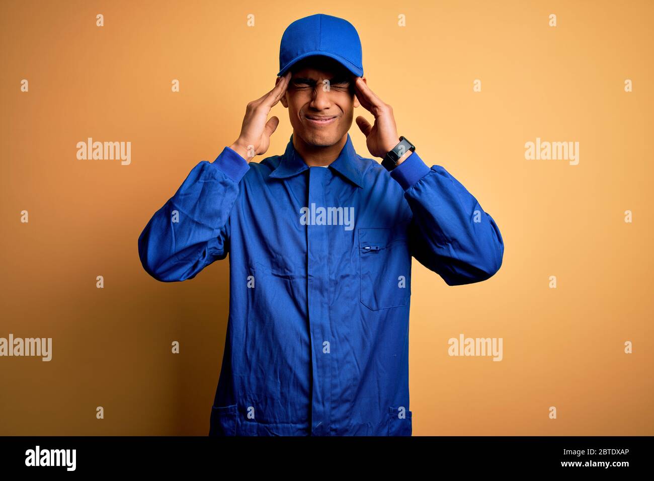 Young african american mechanic man wearing blue uniform and cap over ...