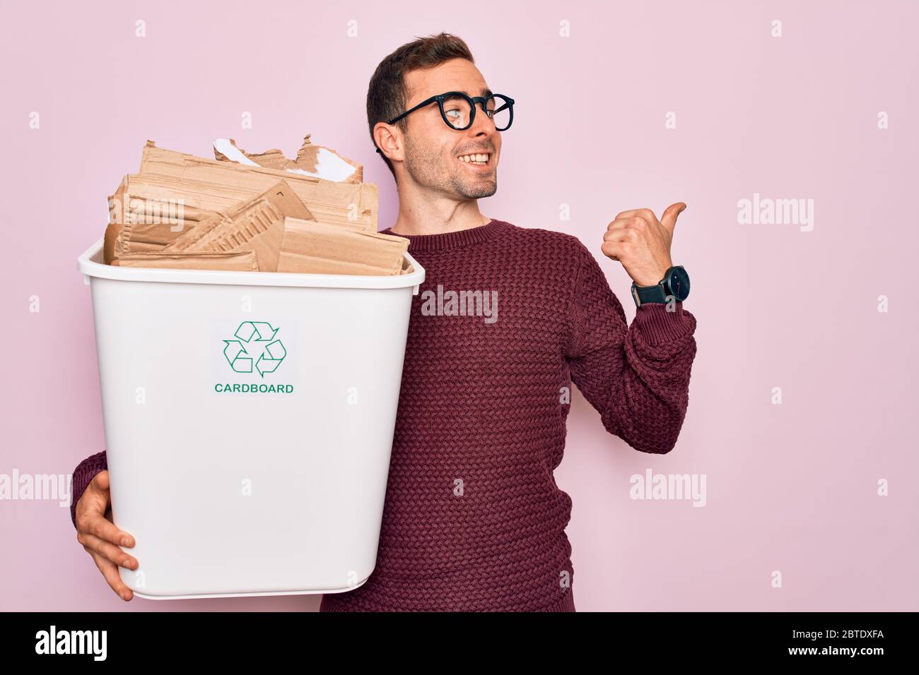 Young handsome man with blue eyes recycling holding wastebasket with ...