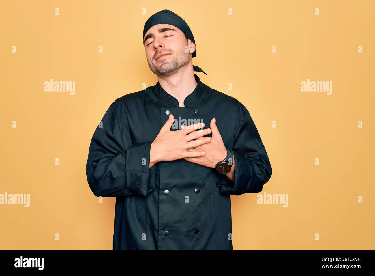 Young handsome cooker man with blue eyes wearing uniform and hat over ...