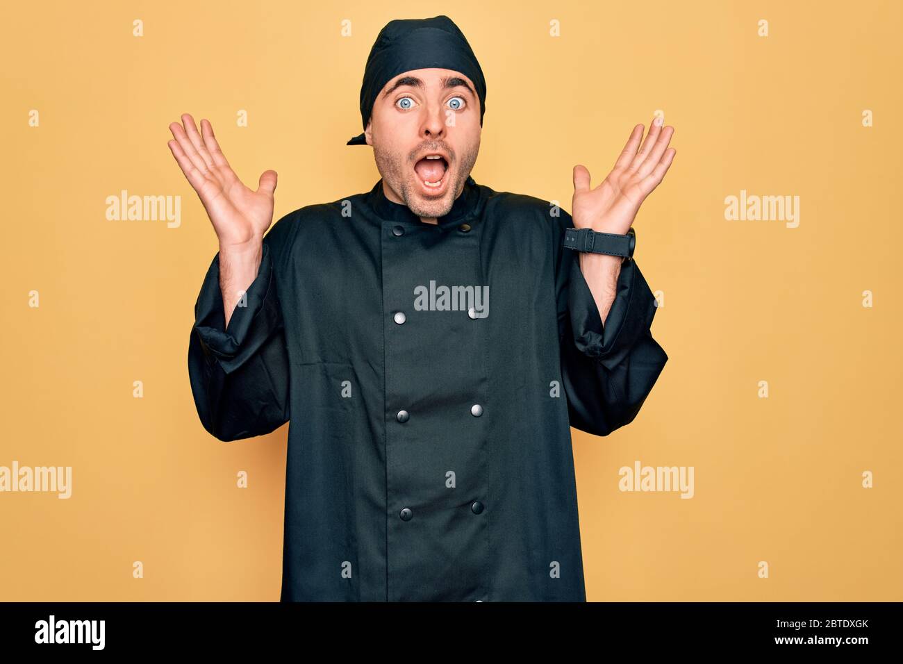 Young handsome cooker man with blue eyes wearing uniform and hat over ...