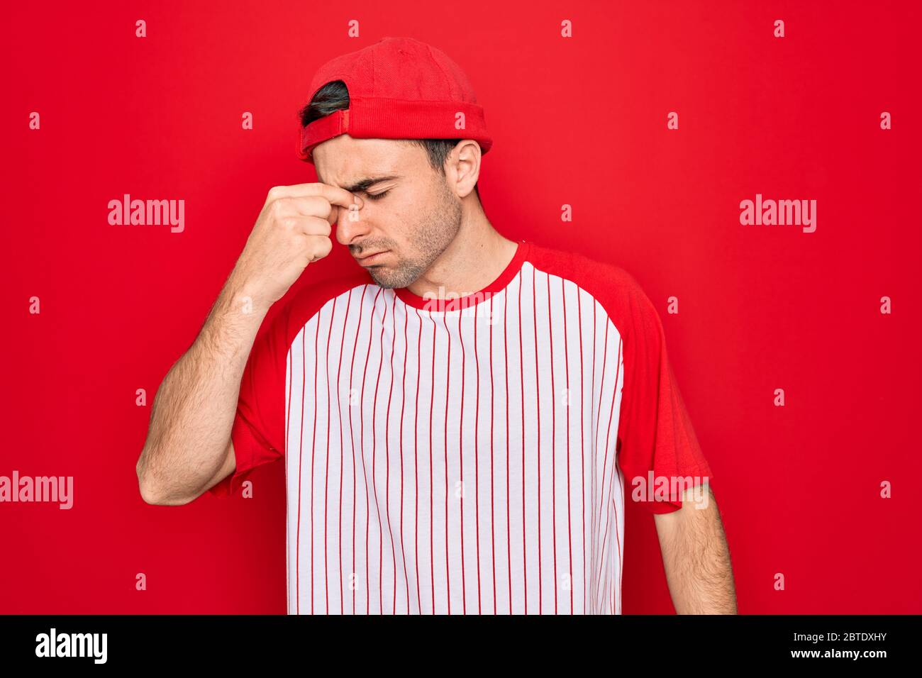 Young handsome sporty man with blue eyes wearing striped baseball t ...