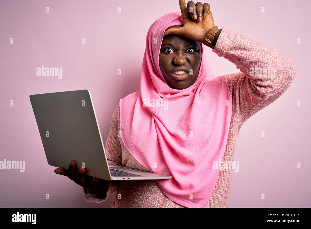 African american plus size woman wearing muslim hijab using laptop over ...