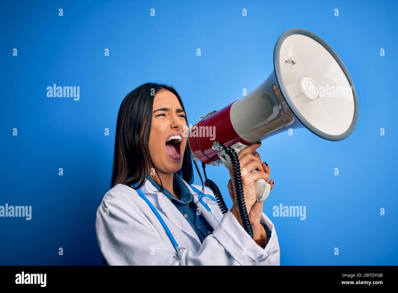 Hispanic doctor woman wearing medical white coat shouting angry on ...