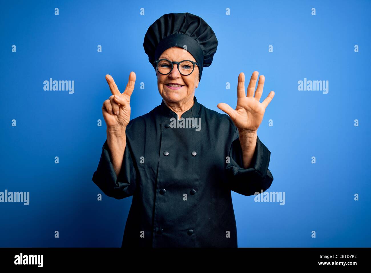 Senior beautiful grey-haired chef woman wearing cooker uniform and hat ...