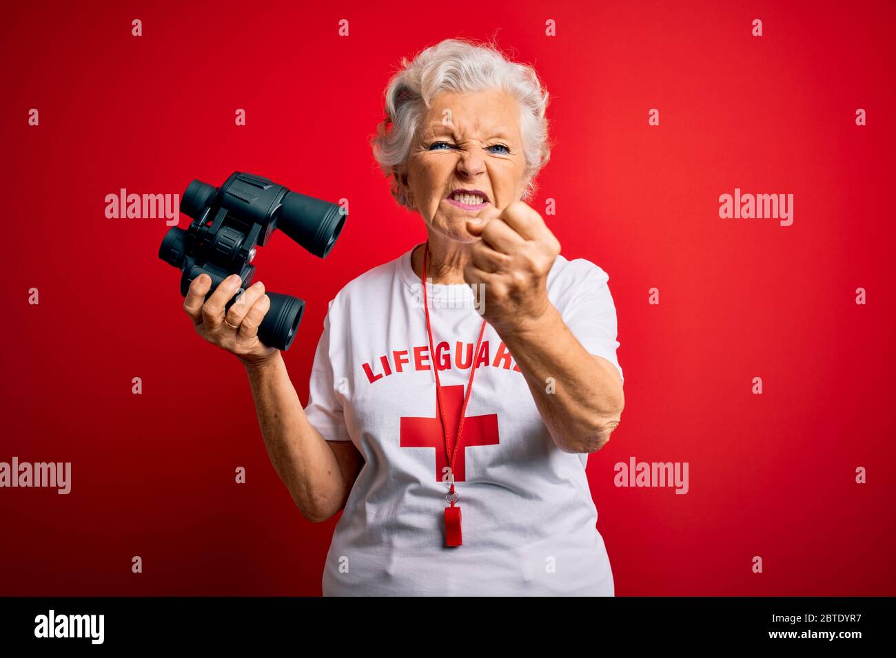 Senior beautiful grey-haired lifeguard woman using binoculars and ...